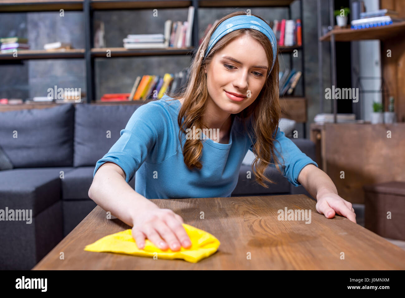 Young smiling woman wiping table with yellow rag Stock Photo - Alamy