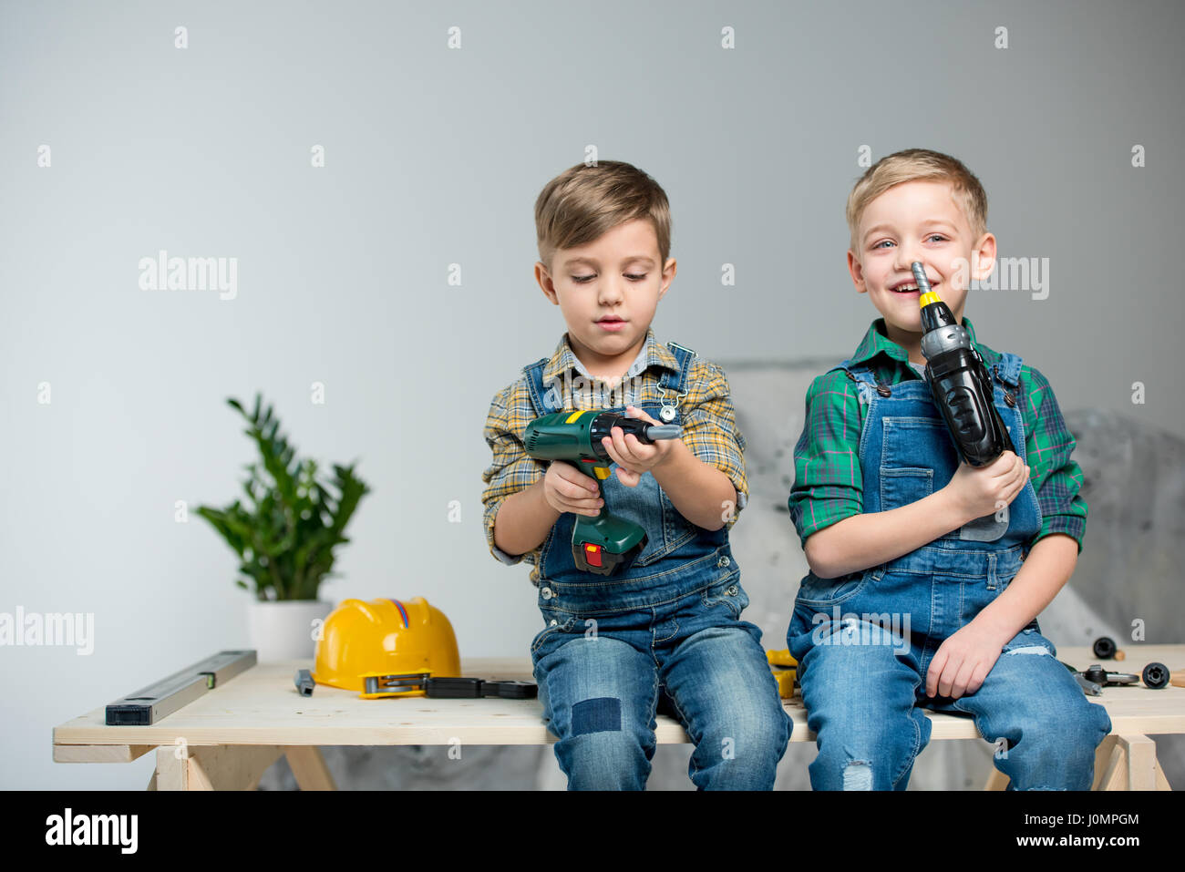 Two little boys playing with toy tools in workshop Stock Photo - Alamy