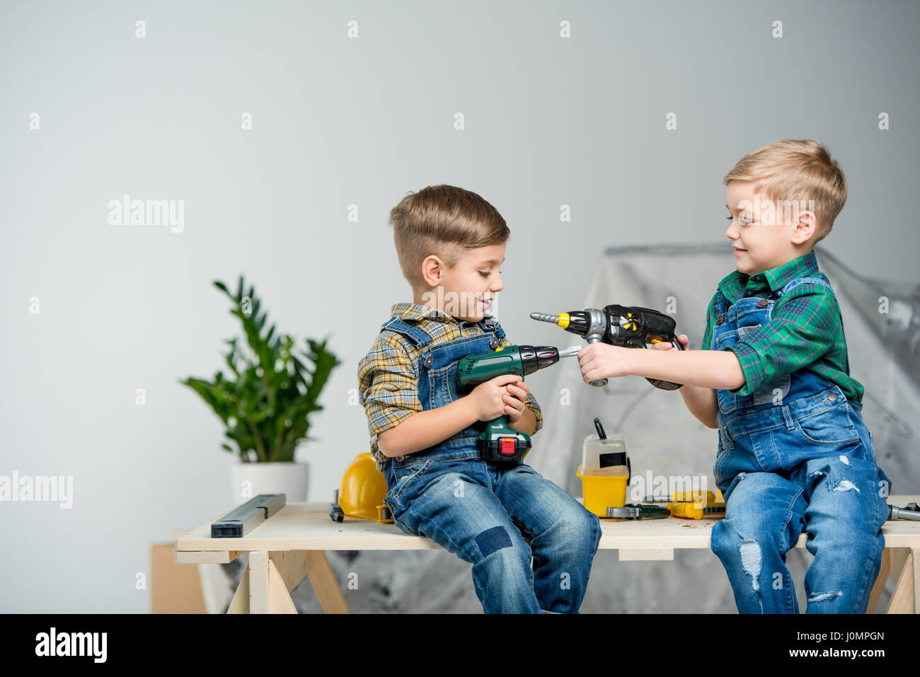 Two little boys playing with toy tools in workshop Stock Photo - Alamy