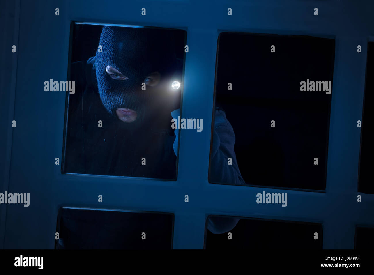 Burglar with flashlight looking through the window Stock Photo - Alamy