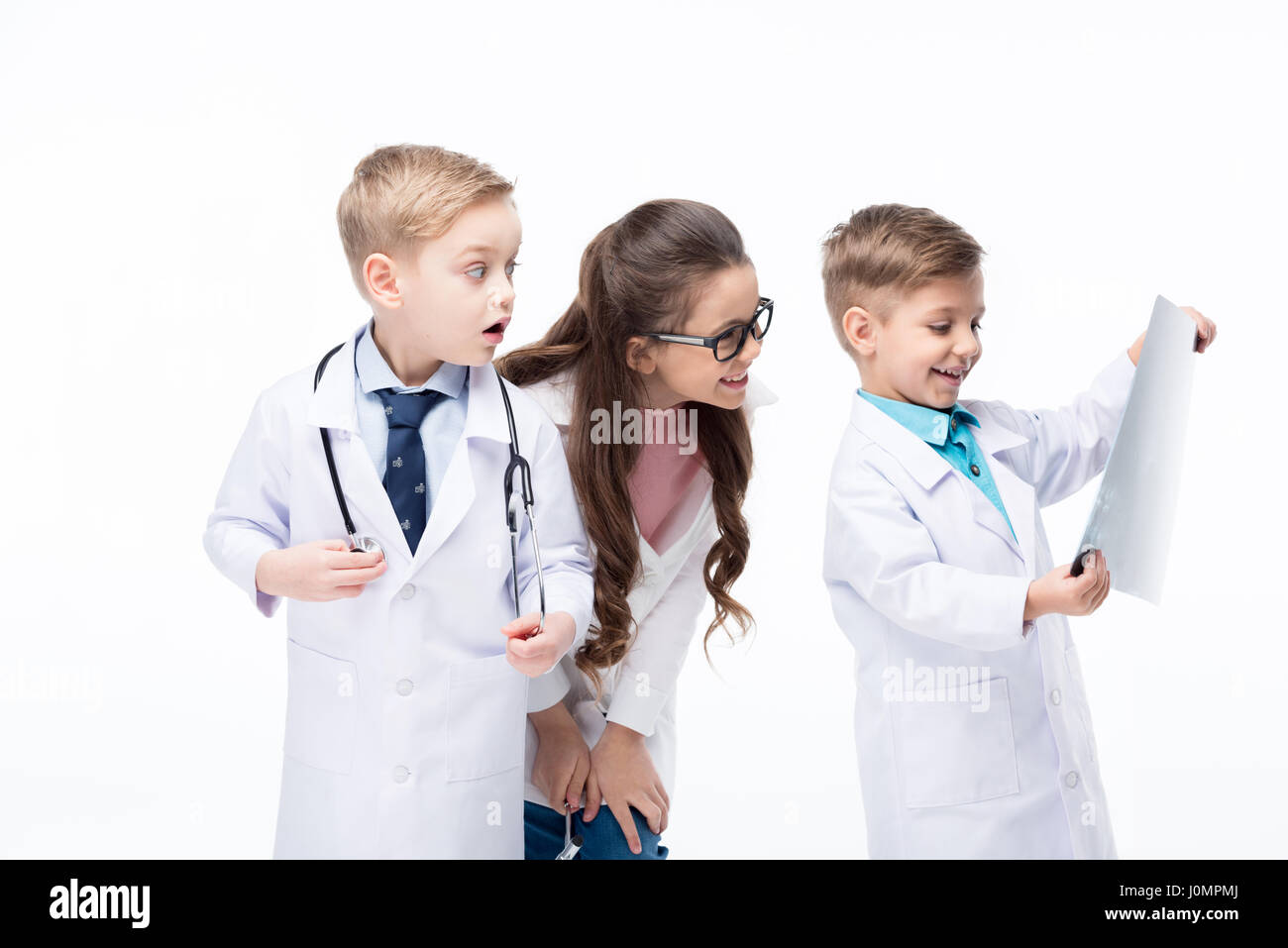 Three cute kids in medical uniform playing doctors and looking at x-ray ...