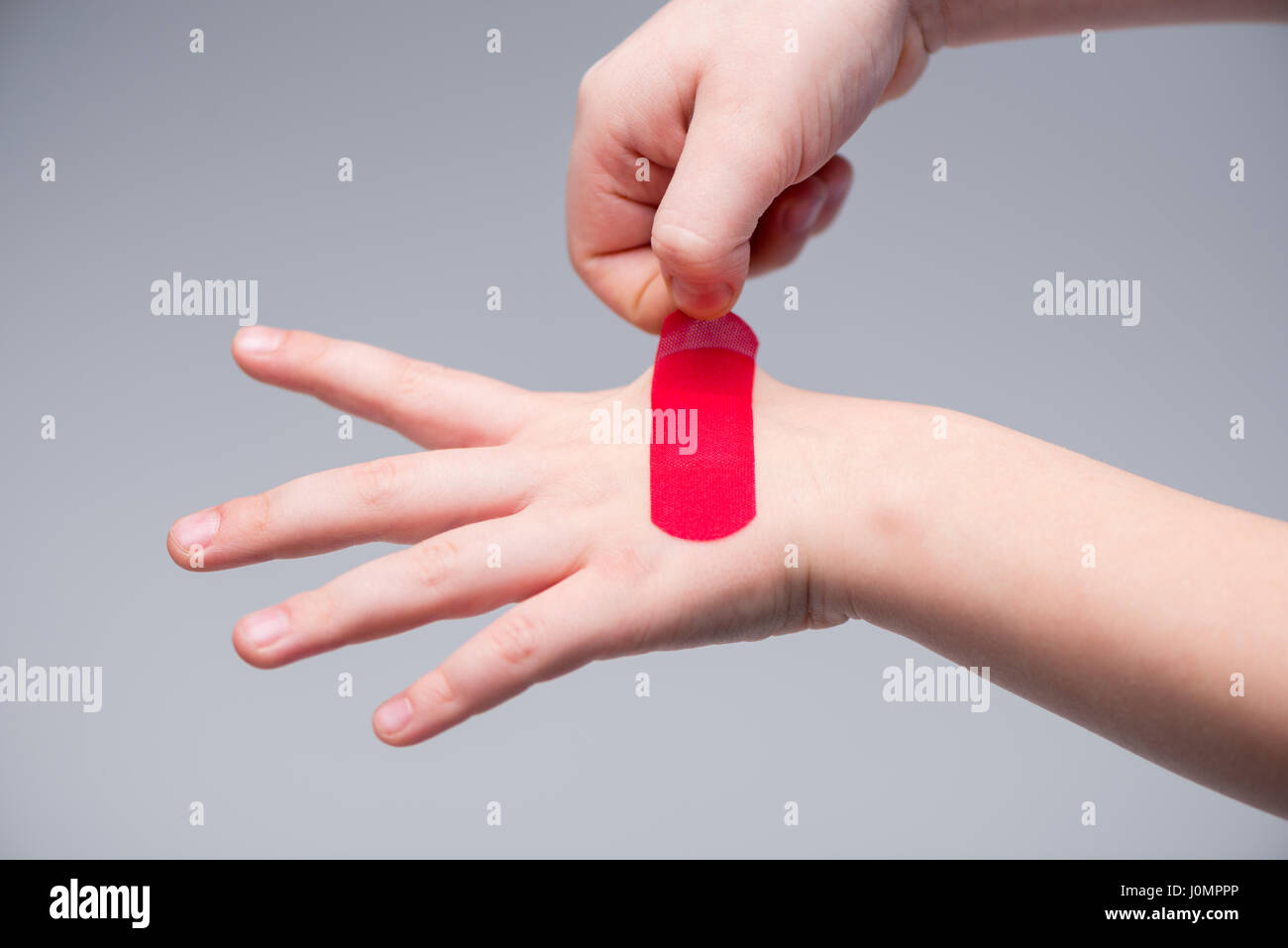 Close-up partial view of child removing red parch from hand Stock Photo ...
