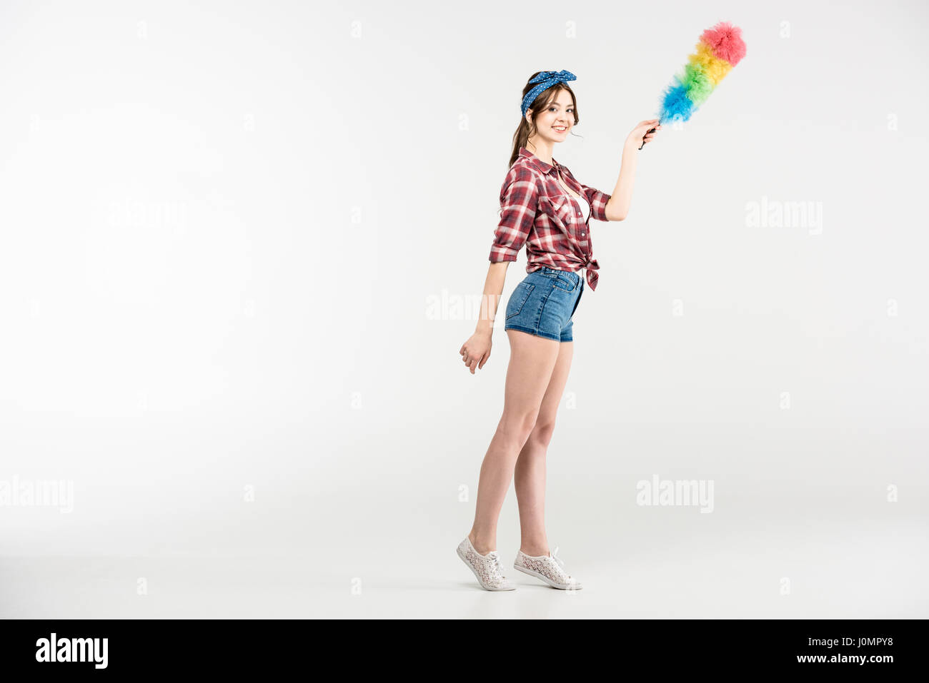 Beautiful young housewife holding colorful duster and smiling at camera ...