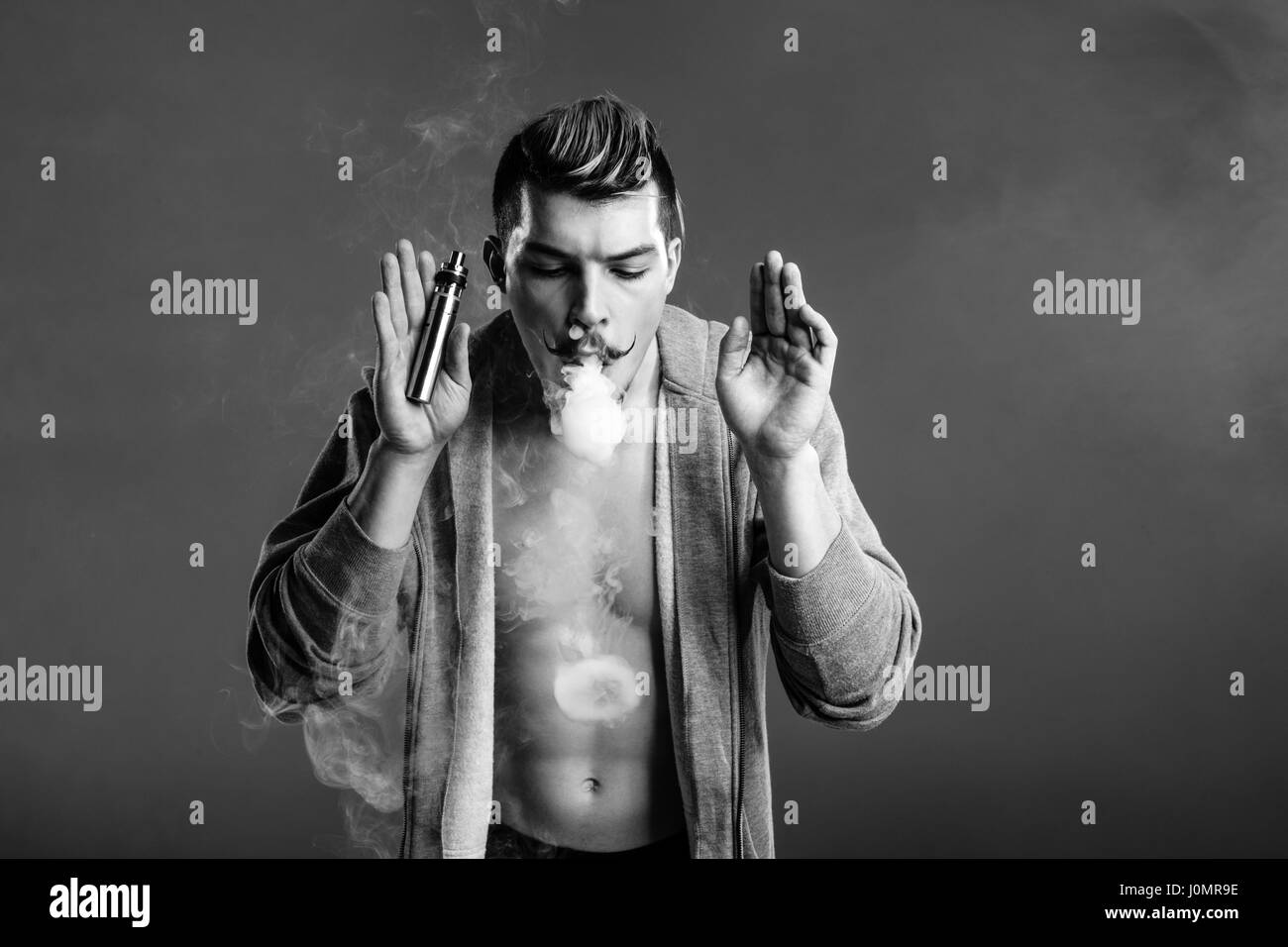 Black and white photo of young handsome man vaping and making smoke ...