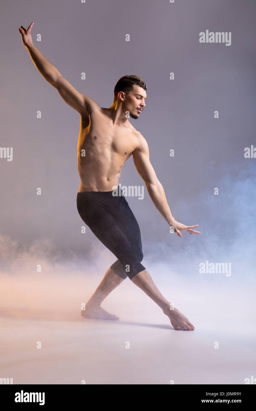 Handsome shirtless young man dancing in smoke on grey Stock Photo - Alamy