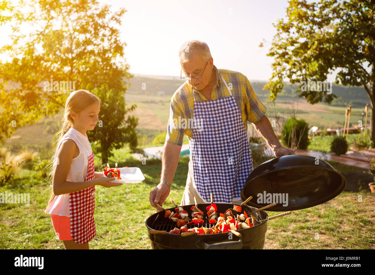 Grandfather and granddaughter preparing barbecue in countryside Stock ...
