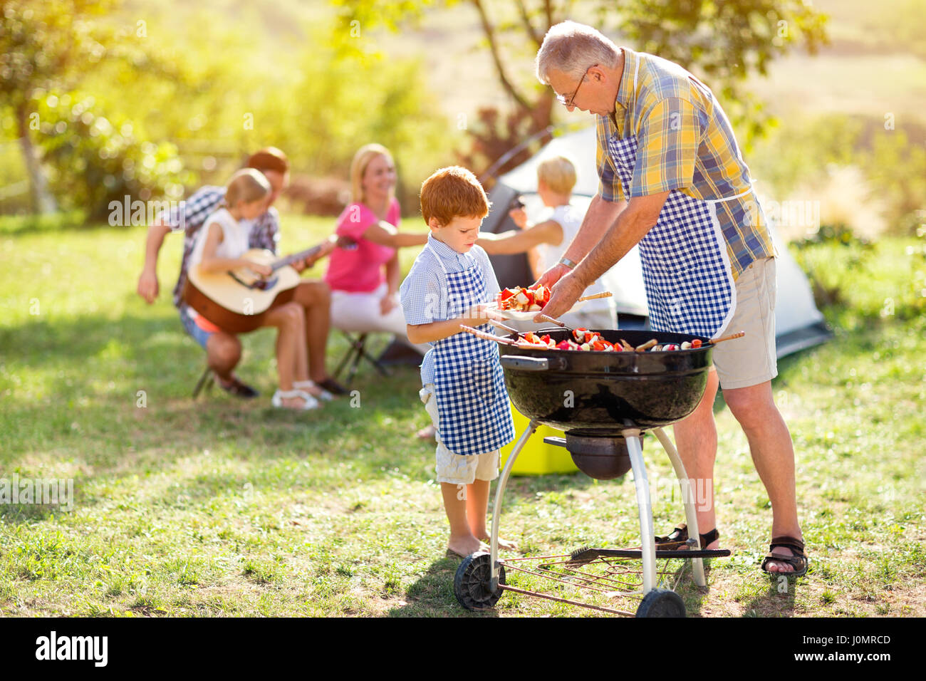grandfather giving grandson barbecue food for family Stock Photo - Alamy