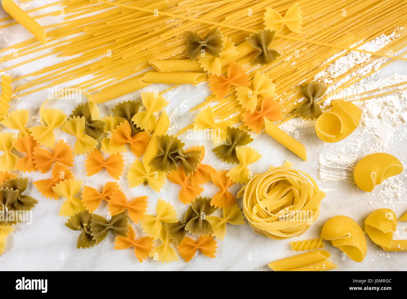 An overhead photo of various types of pasta on a white marble table ...