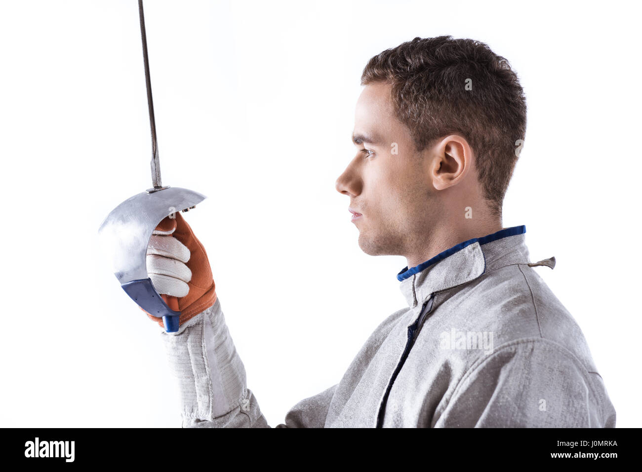 Side view of young man professional fencer holding rapier on white ...