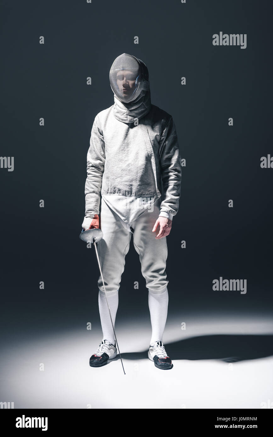 Professional fencer in fencing mask with rapier standing on grey Stock ...