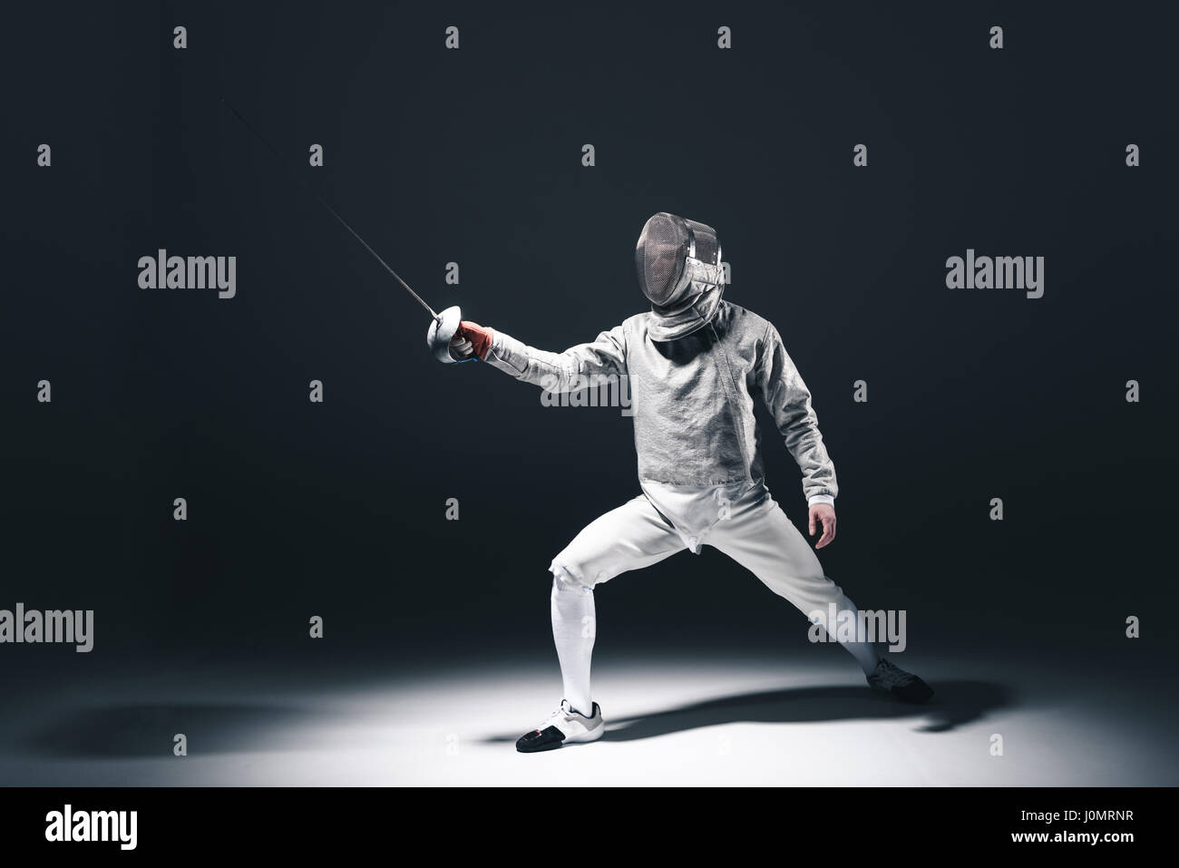 Professional fencer in fencing mask with rapier standing in position on ...