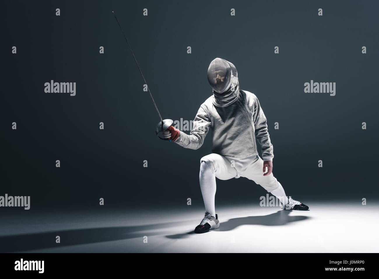 Professional fencer in fencing mask with rapier standing in position on ...