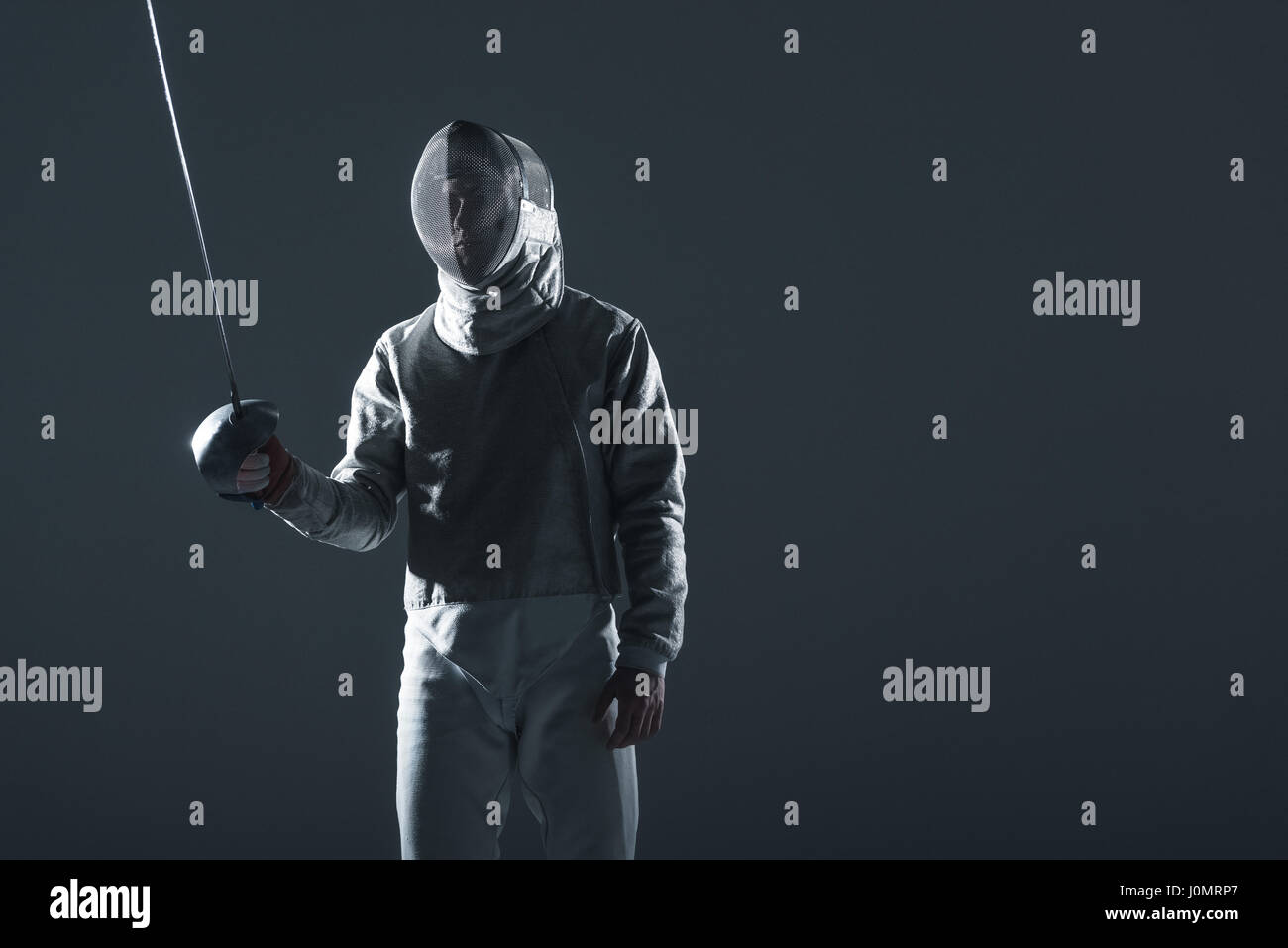 Professional fencer in fencing mask with rapier standing in position on ...