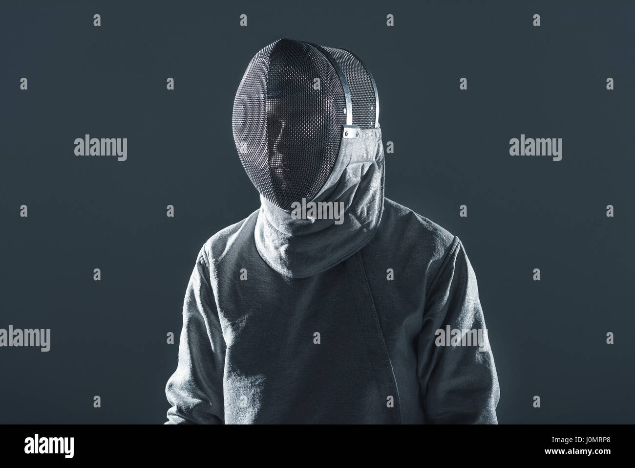 Portrait of professional fencer in fencing mask standing on grey Stock ...