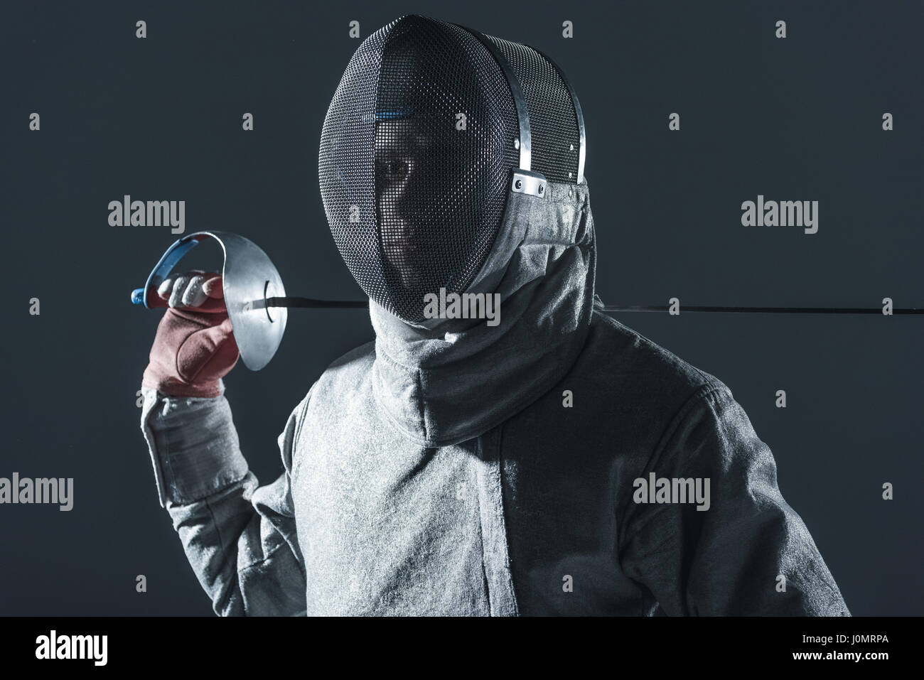 Portrait of professional fencer in fencing mask with rapier on grey ...