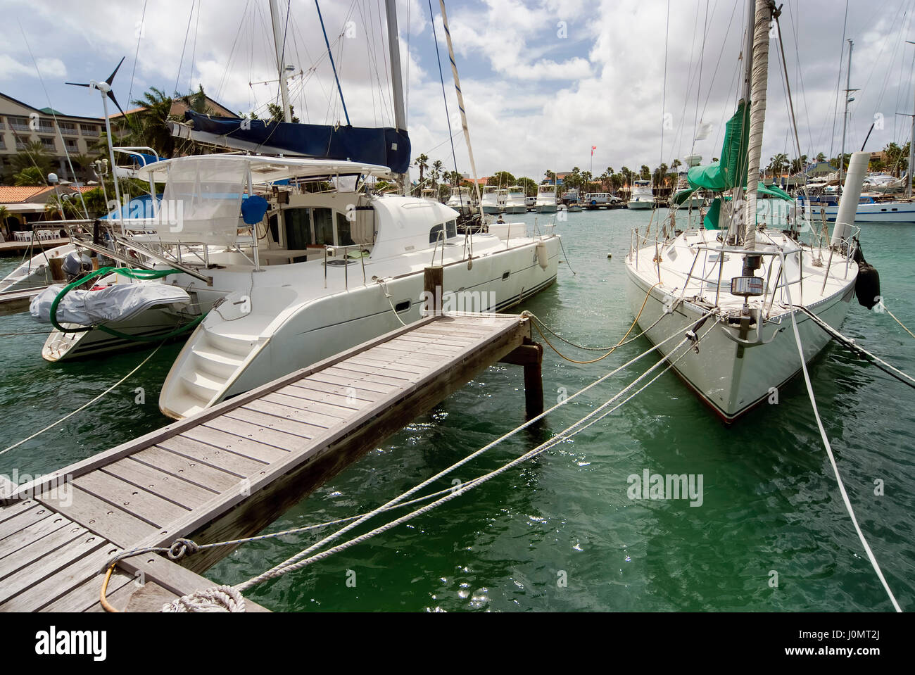 Catamaran and a sailboat moored at the port of Aruba on a sunny day ...