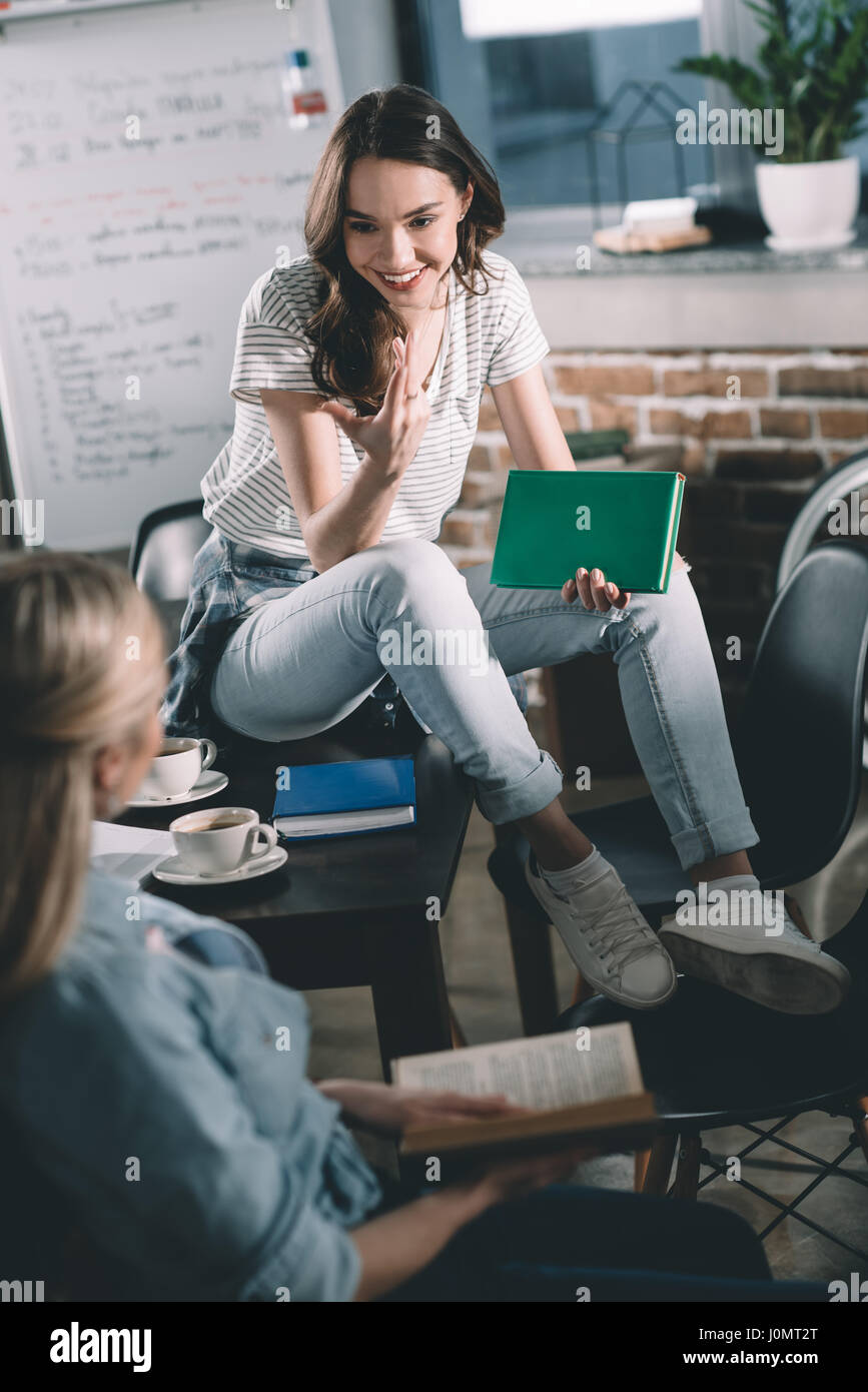 smiling women students having conversation while studying together ...