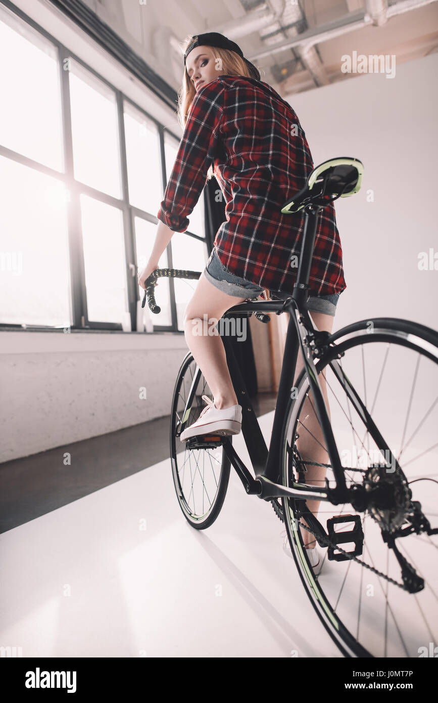 back view of young stylish woman riding bicycle Stock Photo - Alamy