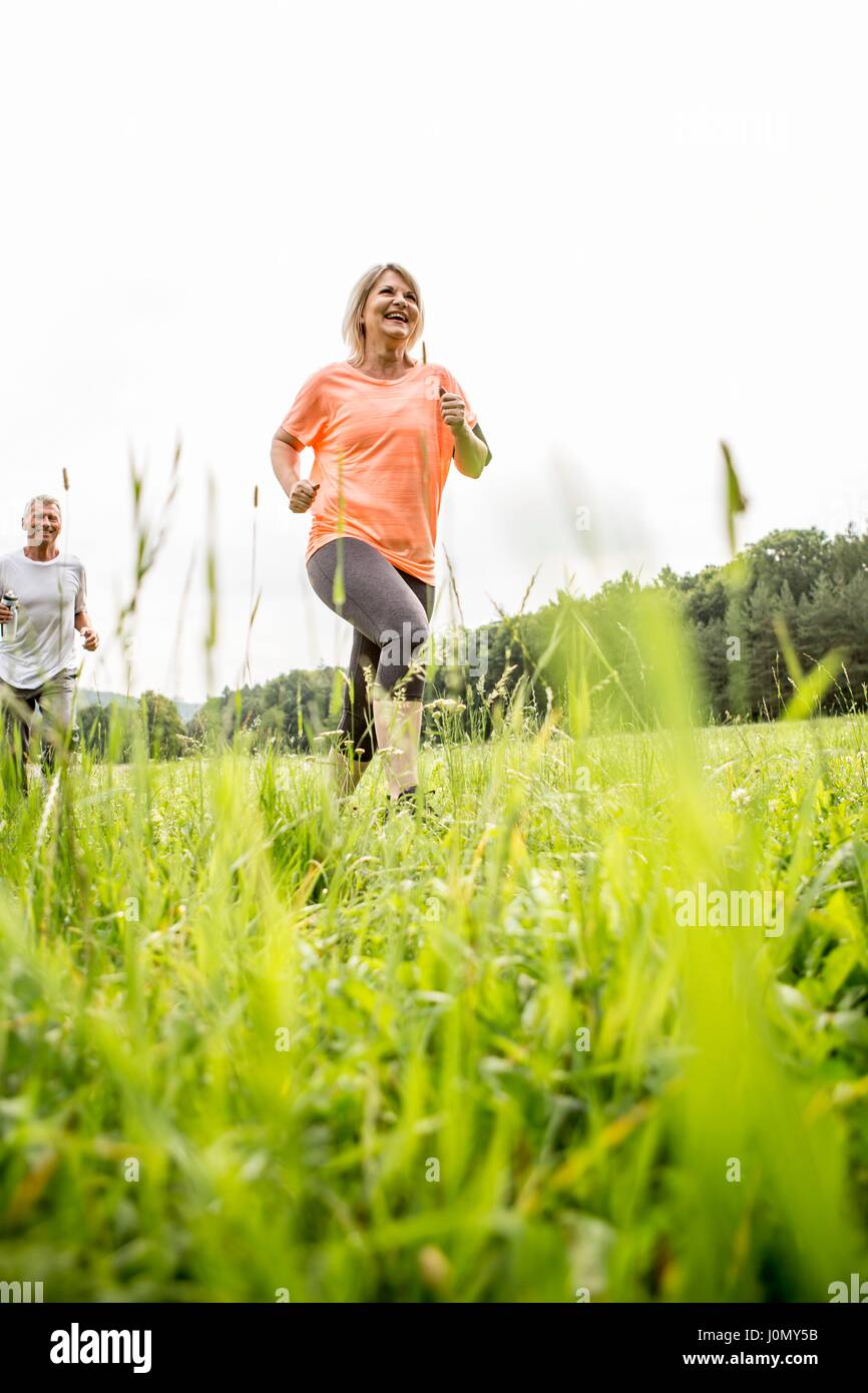 Mature woman jogging in grass Stock Photo - Alamy