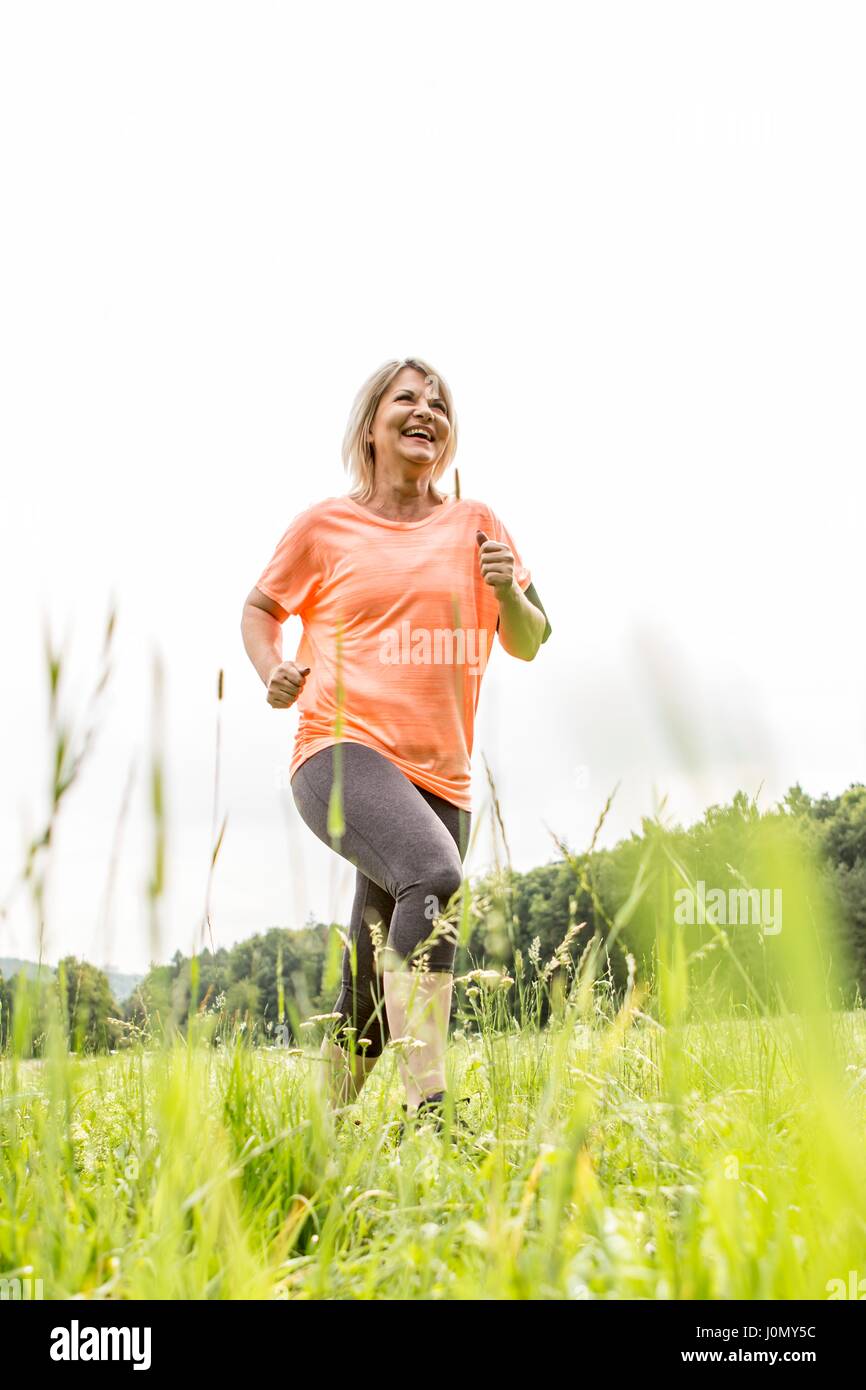 Mature woman jogging in grass Stock Photo - Alamy