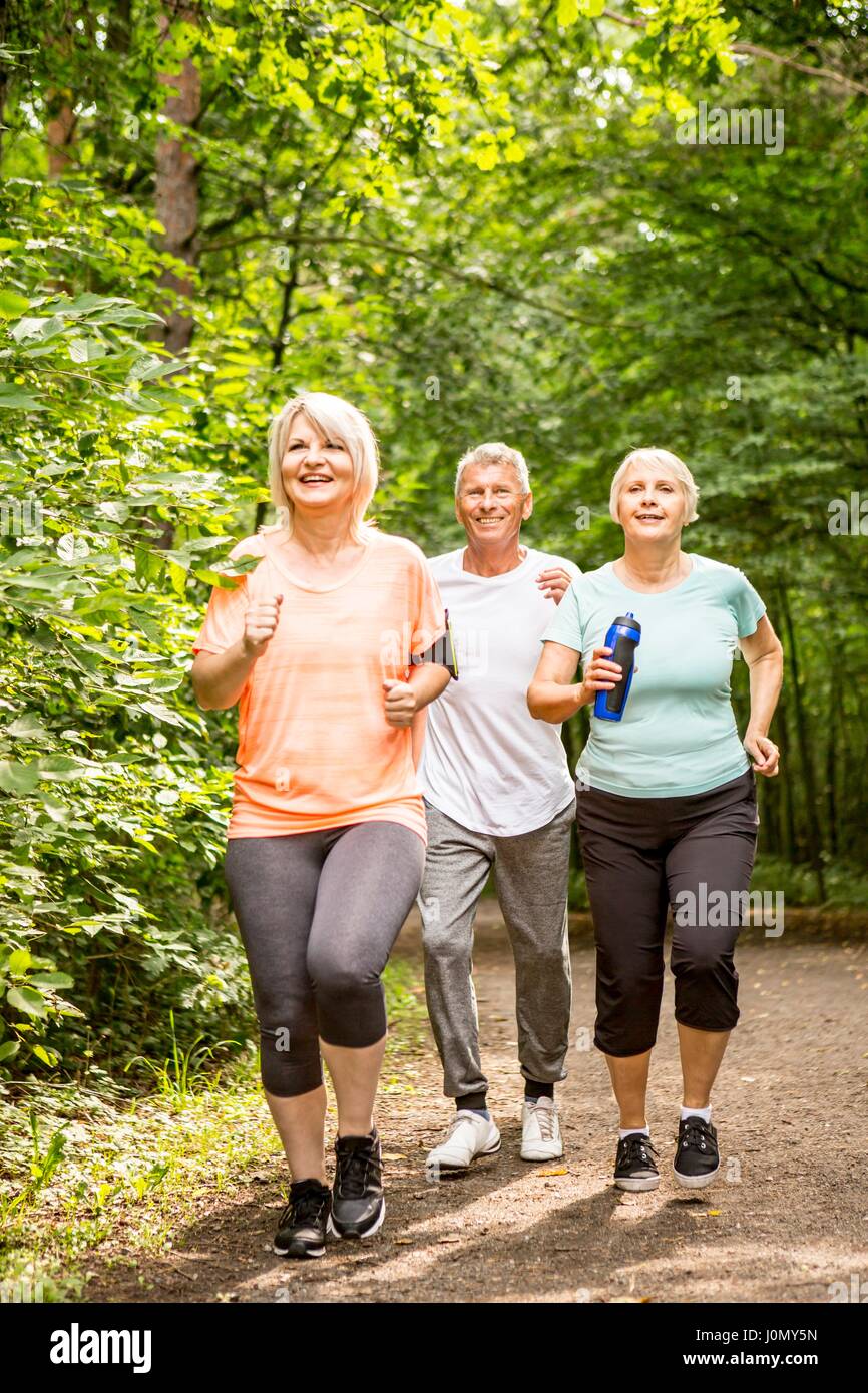 Three people running on track in woods Stock Photo - Alamy