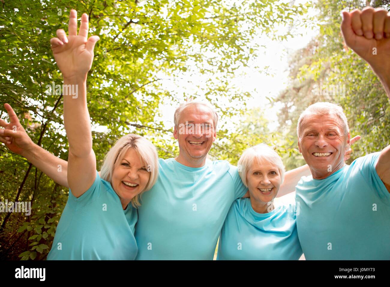 Four people in blue t-shirts, smiling and cheering Stock Photo - Alamy