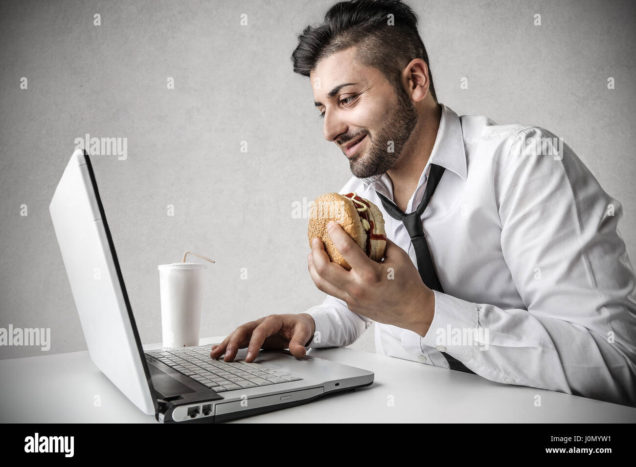 Businessman eating while working Stock Photo - Alamy