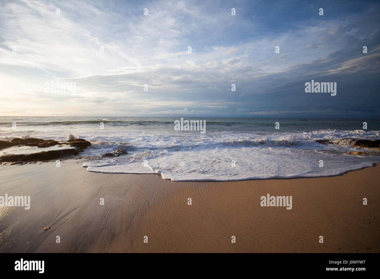Ocean waves breaking on the rocks on the beach with the reflection of ...