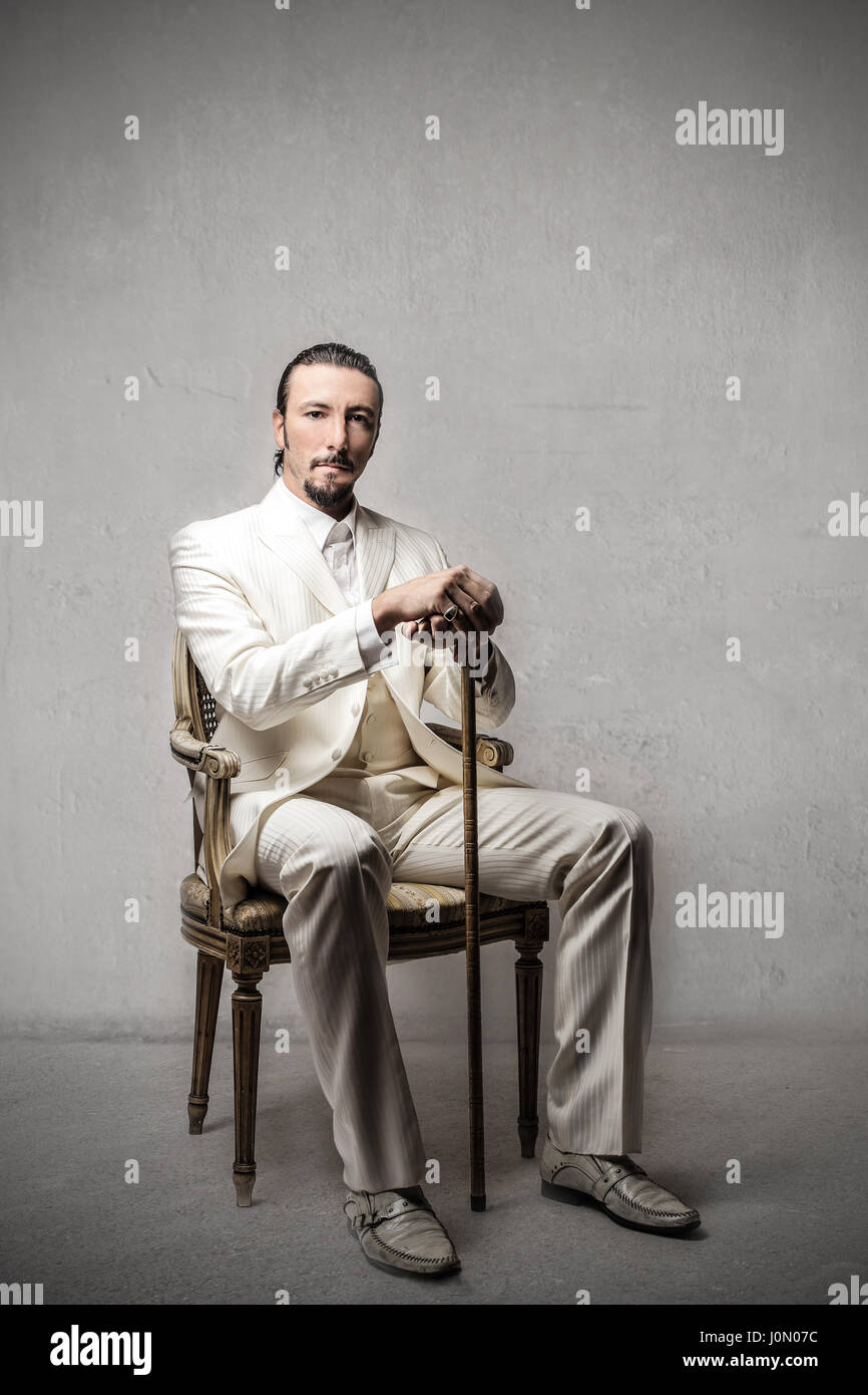 Man in white suit sitting on chair Stock Photo - Alamy