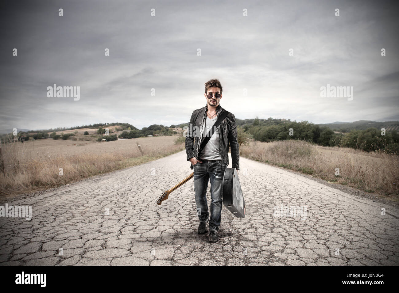 Rocker man walking on road Stock Photo - Alamy