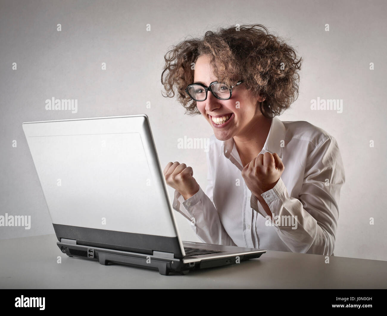 Happy businesswoman cheering in front of laptop Stock Photo - Alamy