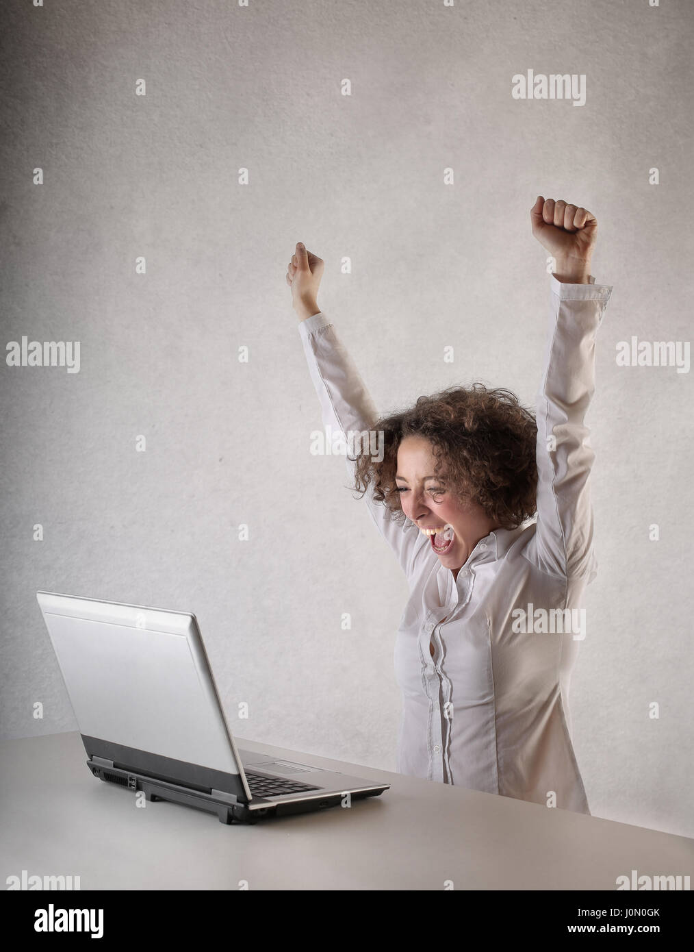 Businesswoman cheering in front of laptop Stock Photo - Alamy