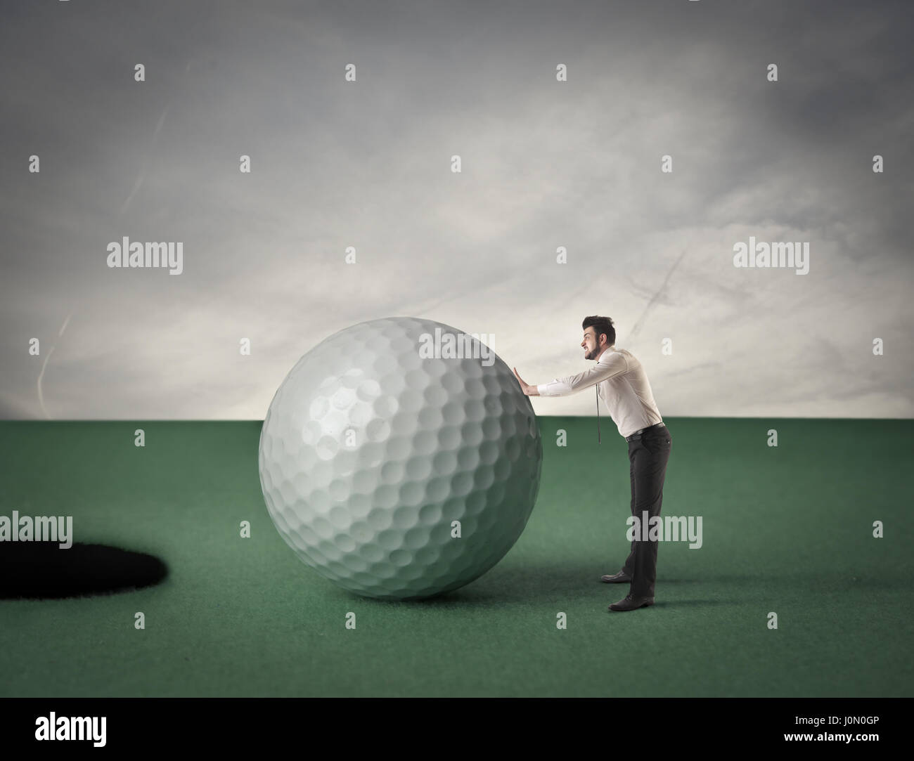 Man holding huge golf ball Stock Photo - Alamy