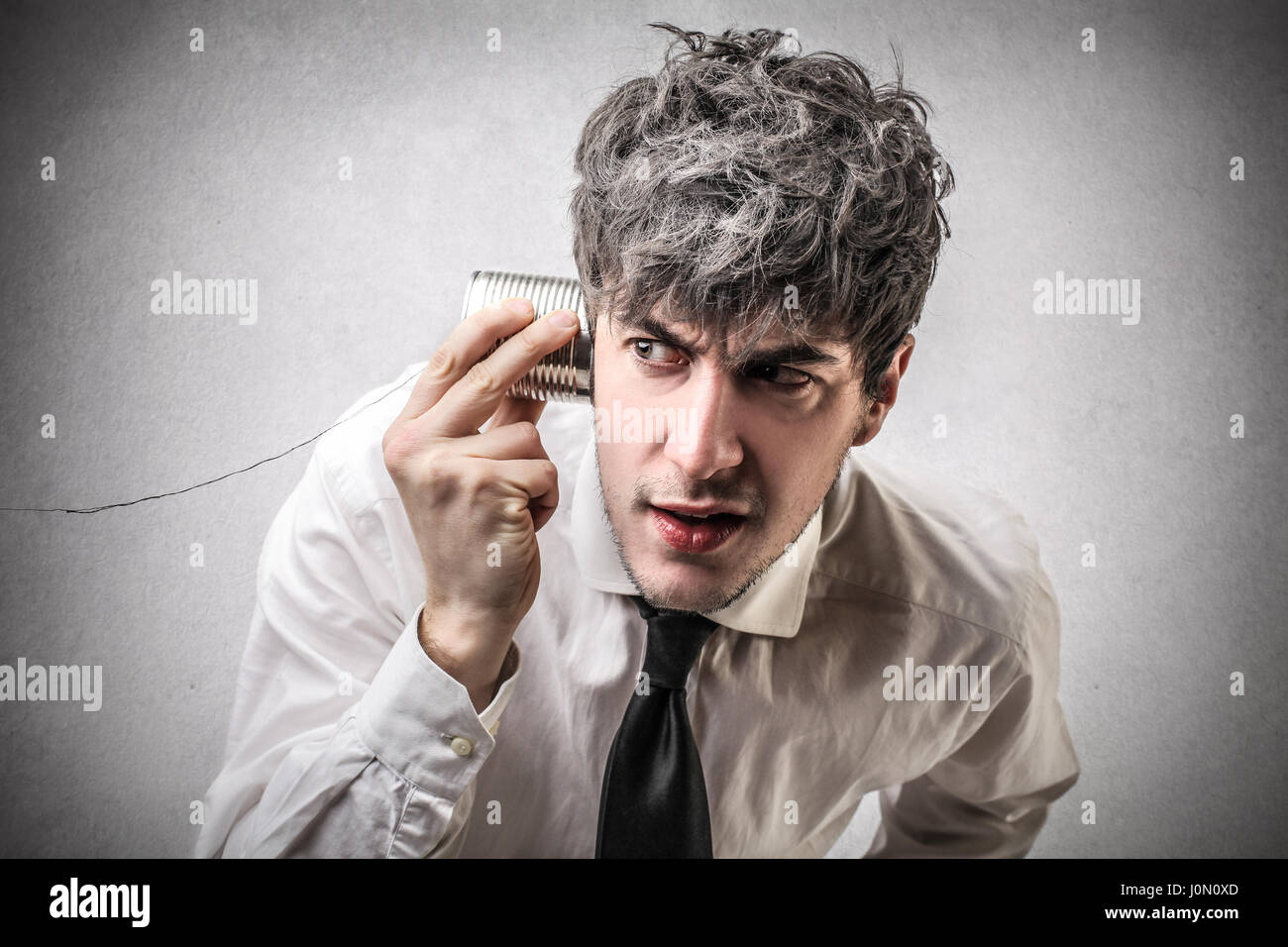 Angry man listening with can and string Stock Photo - Alamy
