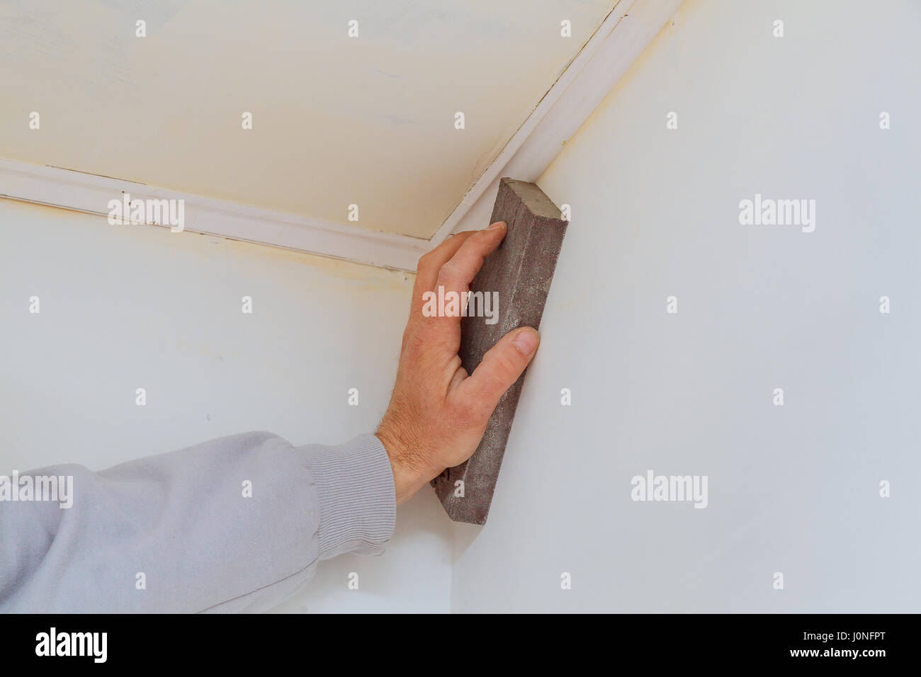 Room repair, hand sanding the wall with a sanding sponge sanding the ...