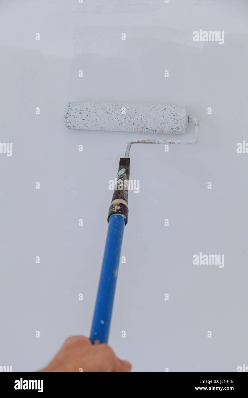 Worker painting wall to white with paint roller paint roller, wall ...