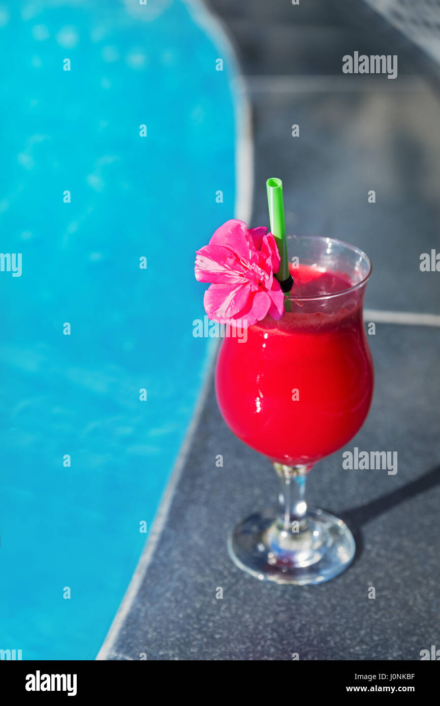 Glass of fresh watermelon smoothie juice drink on border of a swimming ...
