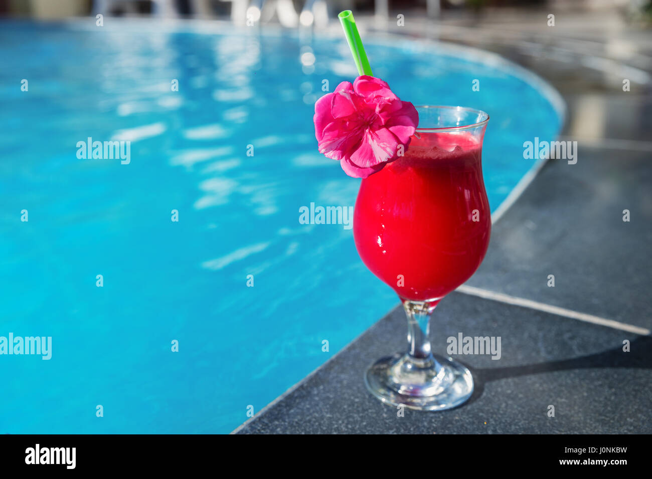 Glass of fresh watermelon smoothie juice drink on border of a swimming ...
