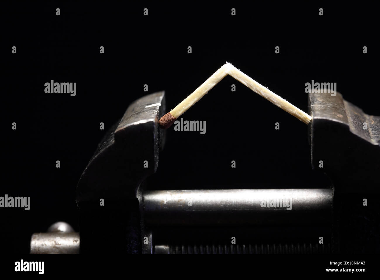 Pressure concept.Cracked match pressured in a bench vice on dark ...