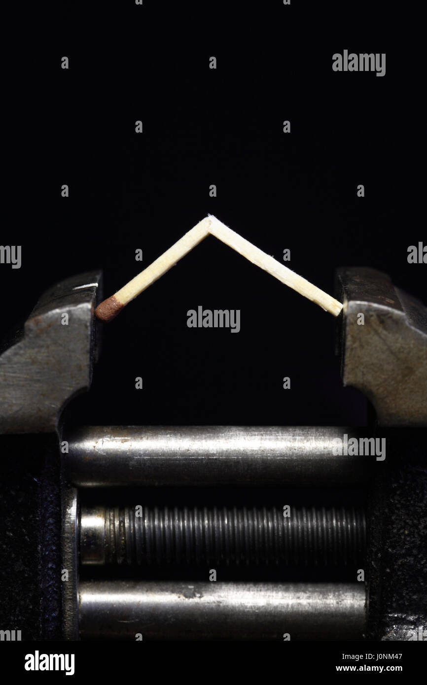 Pressure concept.Cracked match pressured in a bench vice on dark ...