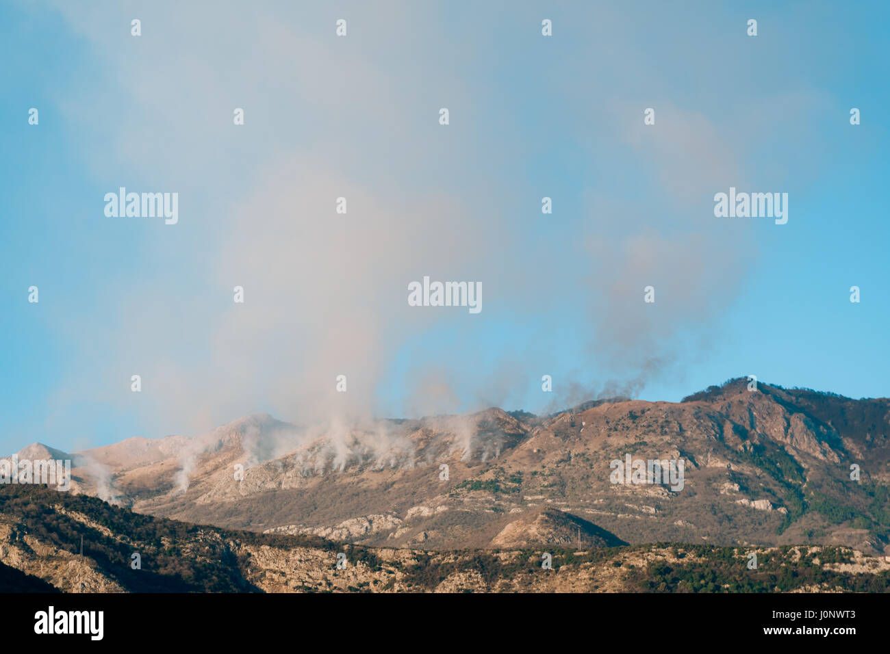 Fire in the mountains in the afternoon. Smoke over the mountains. Budva ...