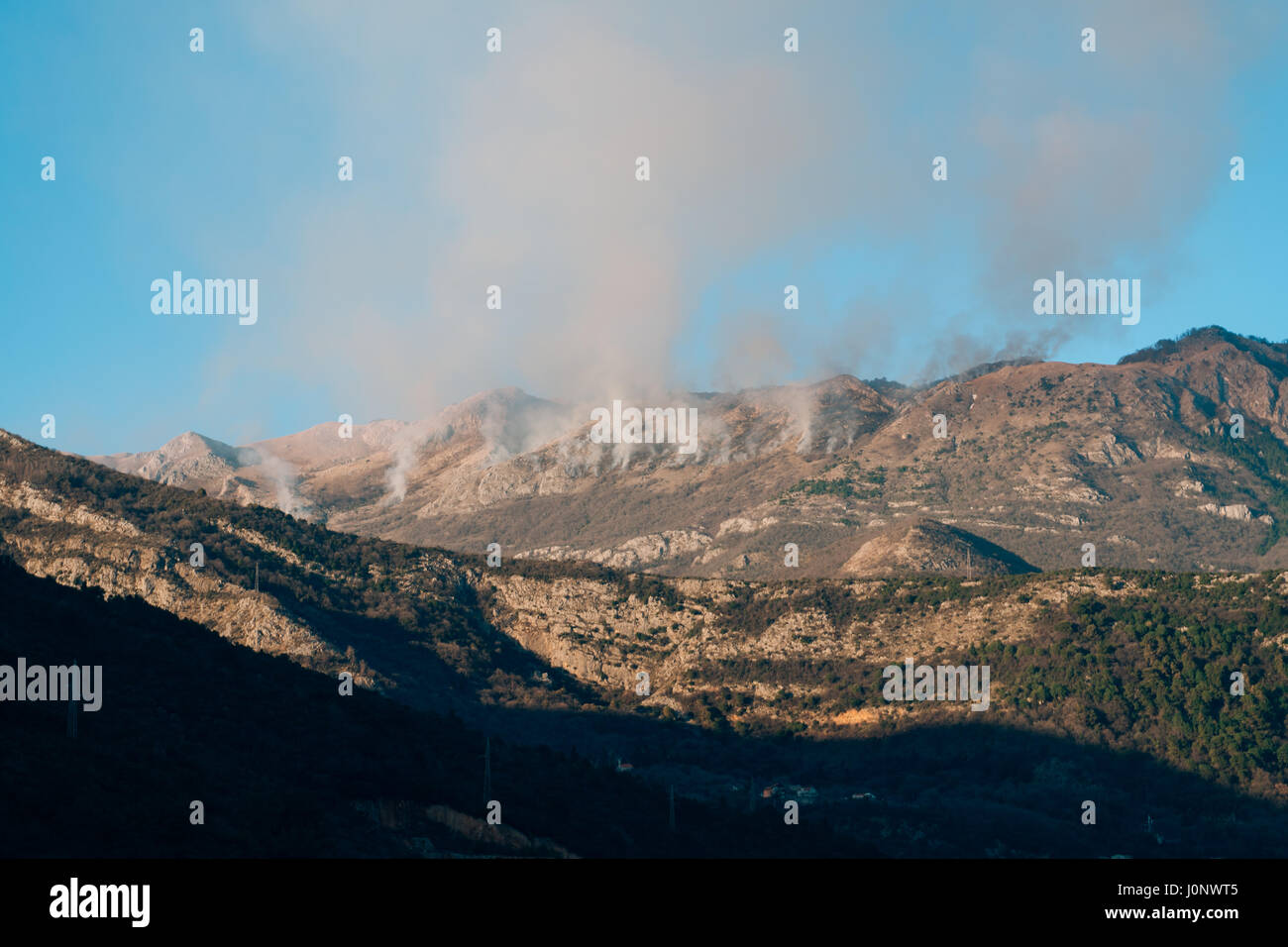 Fire in the mountains in the afternoon. Smoke over the mountains. Budva ...