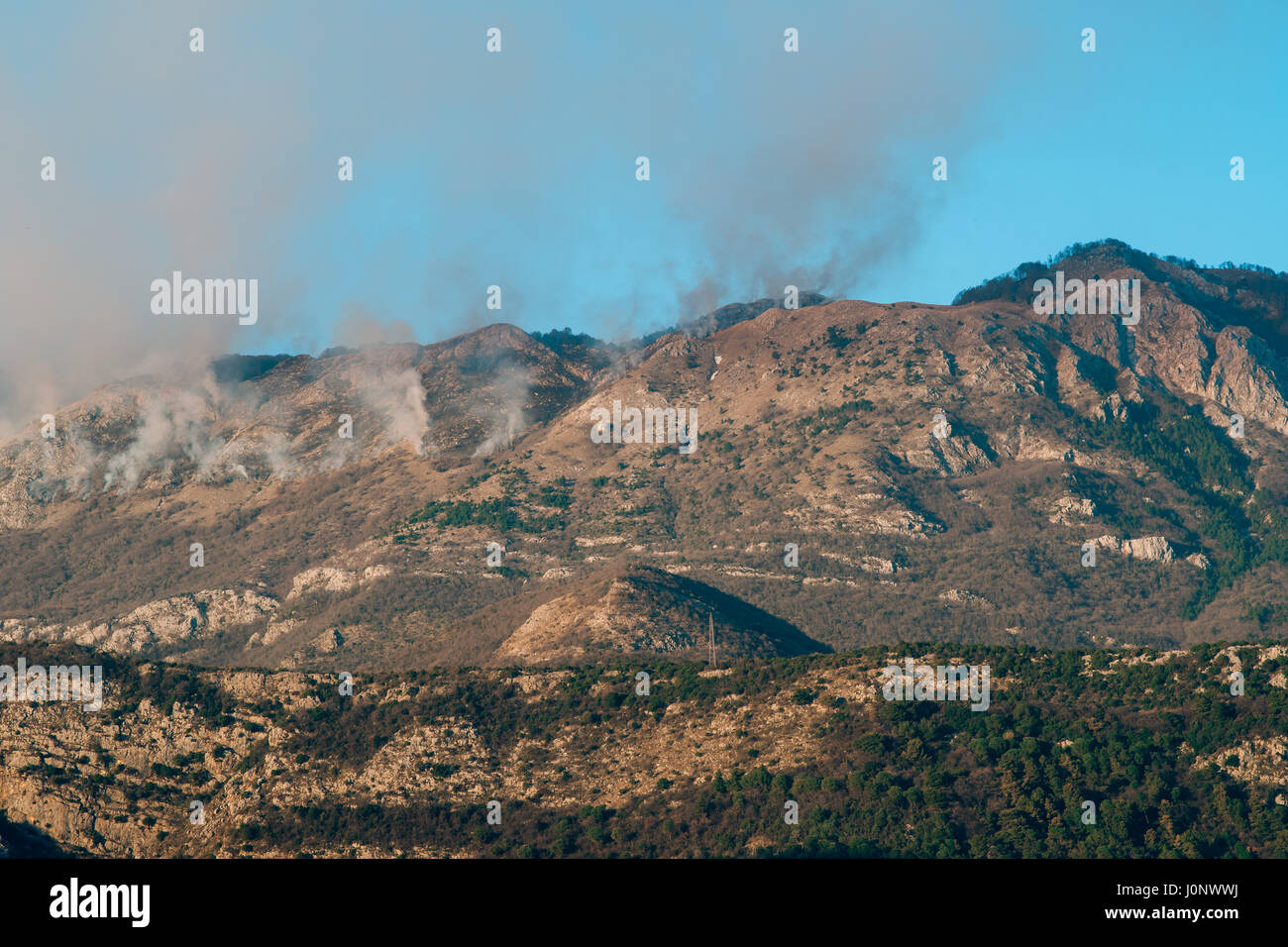 Fire in the mountains in the afternoon. Smoke over the mountains. Budva ...