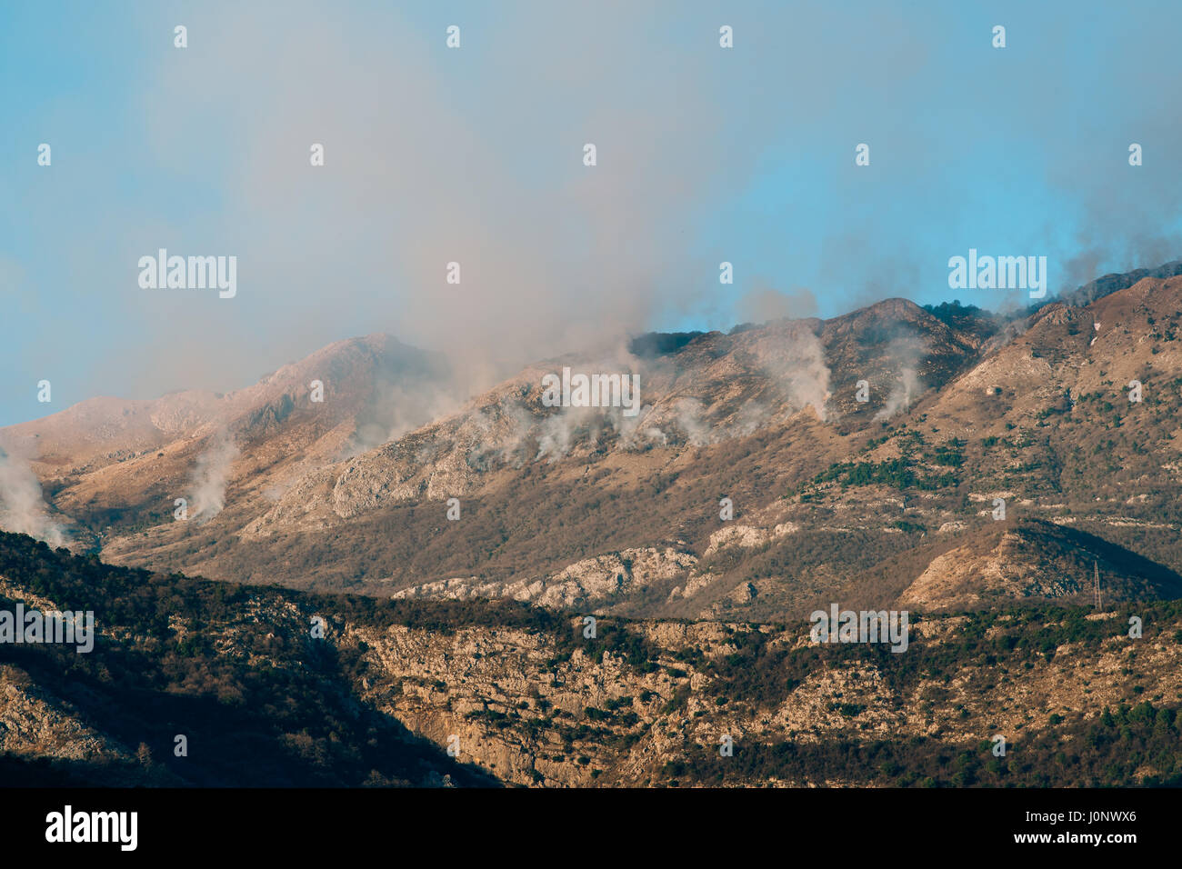 Fire in the mountains in the afternoon. Smoke over the mountains. Budva ...
