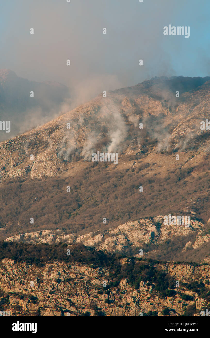 Fire in the mountains in the afternoon. Smoke over the mountains. Budva ...