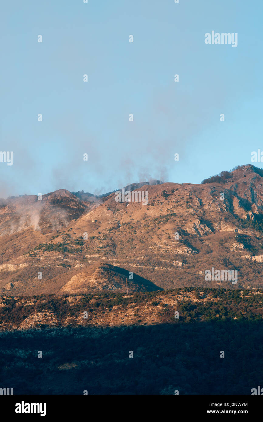 Fire in the mountains in the afternoon. Smoke over the mountains. Budva ...