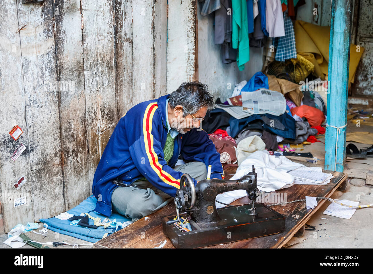 Local Indian man working as a tailor using an old fashioned sewing ...