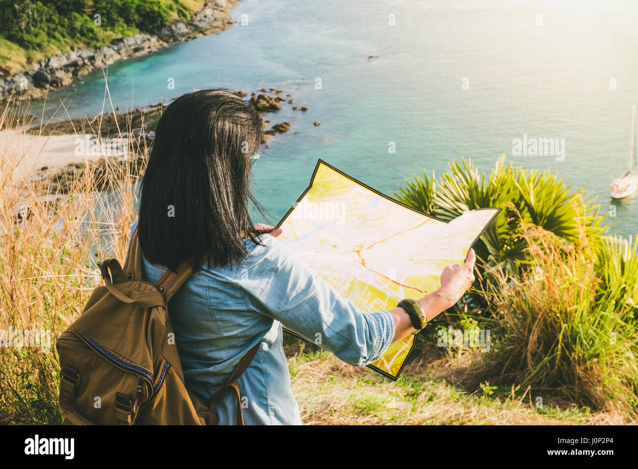 Back of traveler girl with backpack looking direction on map at top of ...
