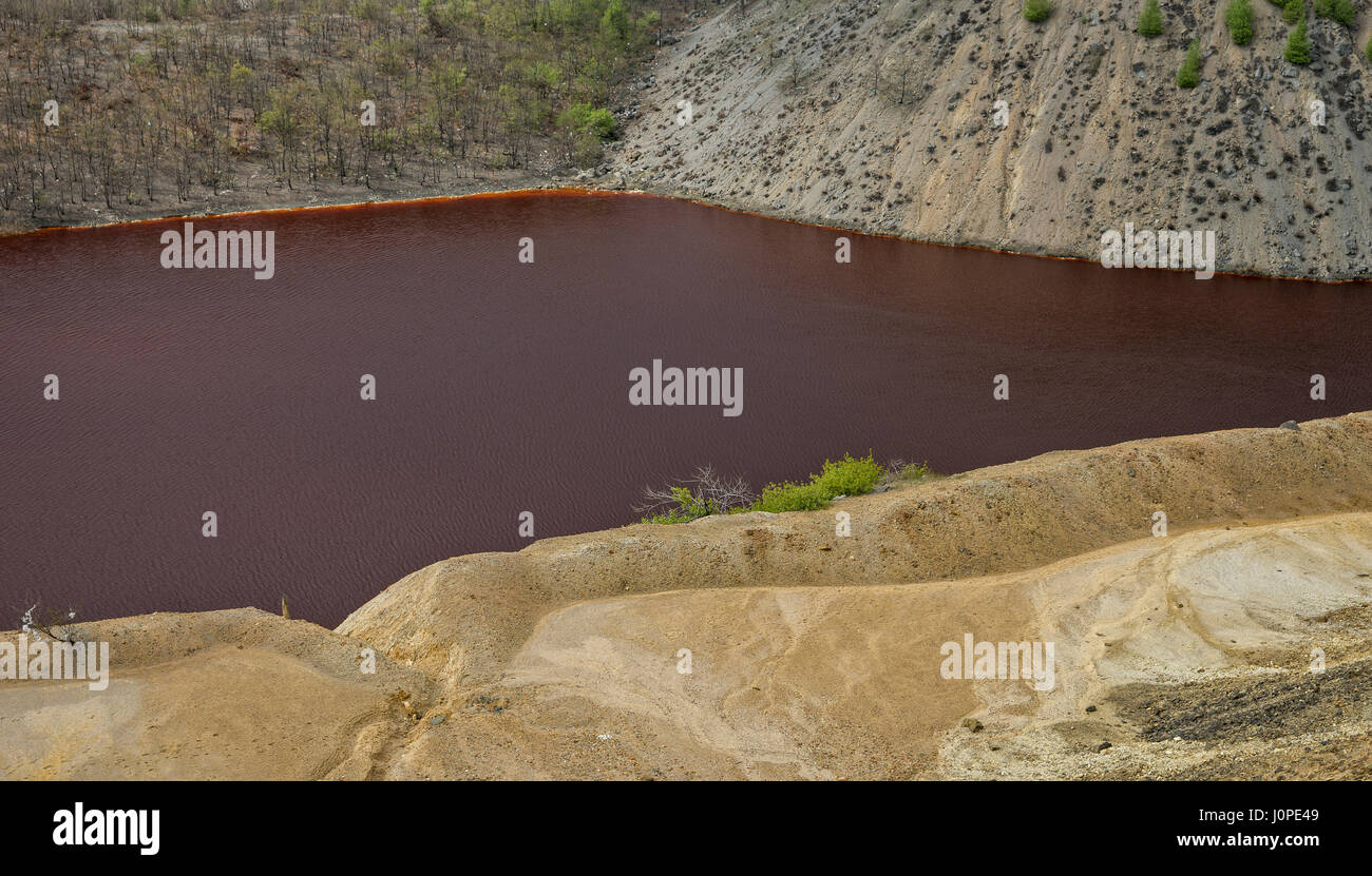 Red artificial lake and hills as a result of mining and production of ...