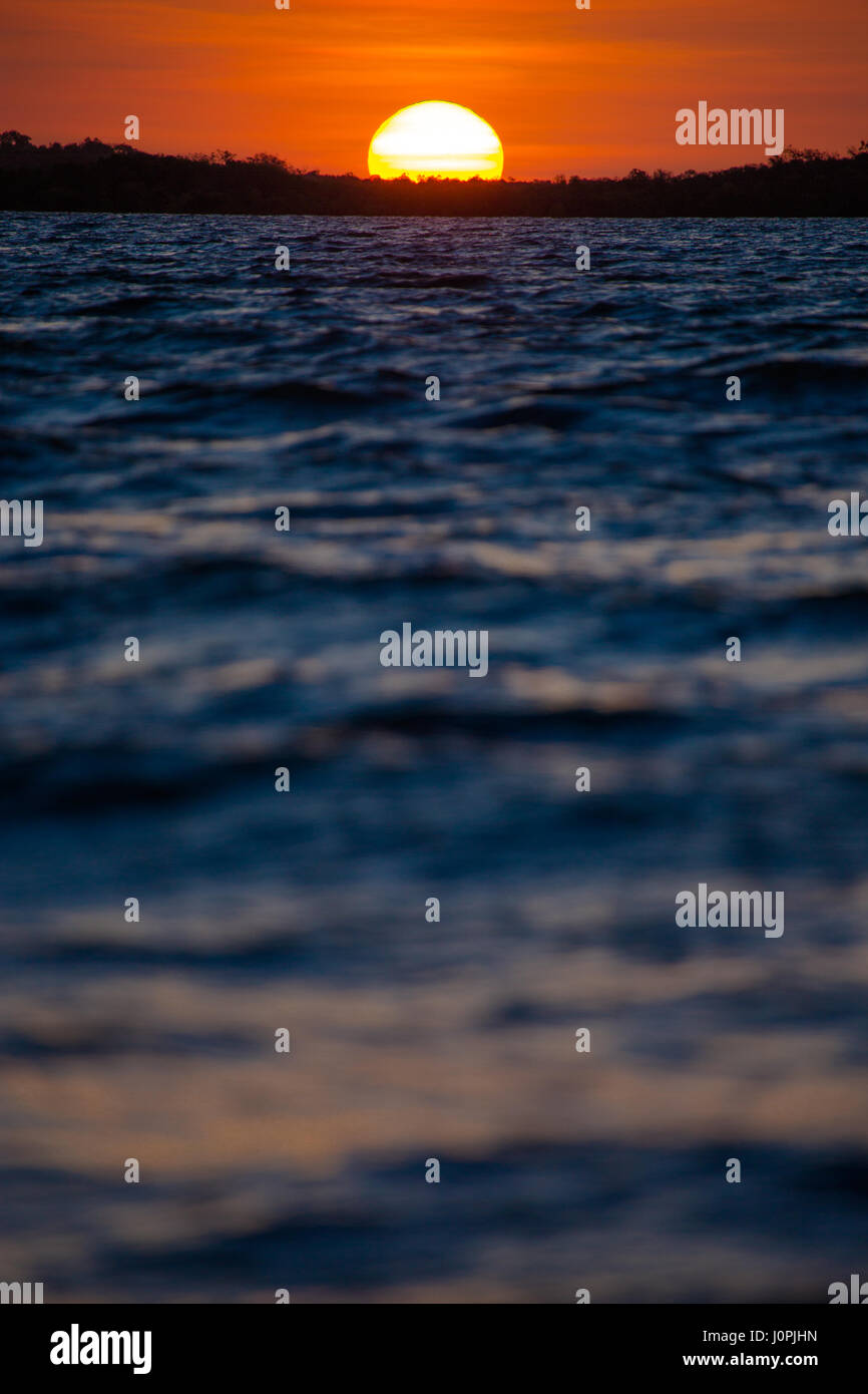 The perfect sun just touches the oceanic horizon, Weipa, North ...